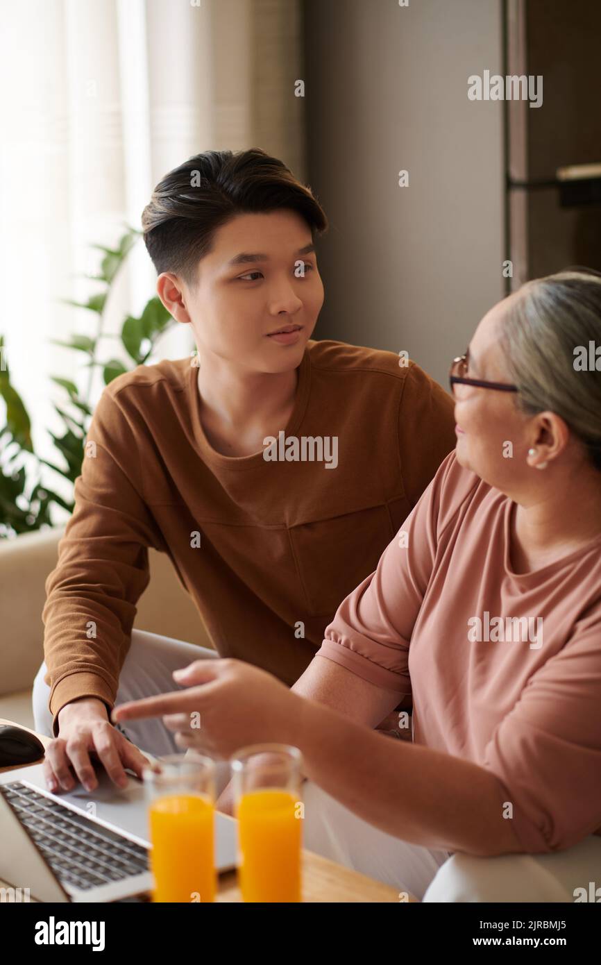 Senior woman asking grandson to show how she can pay bills online Stock ...