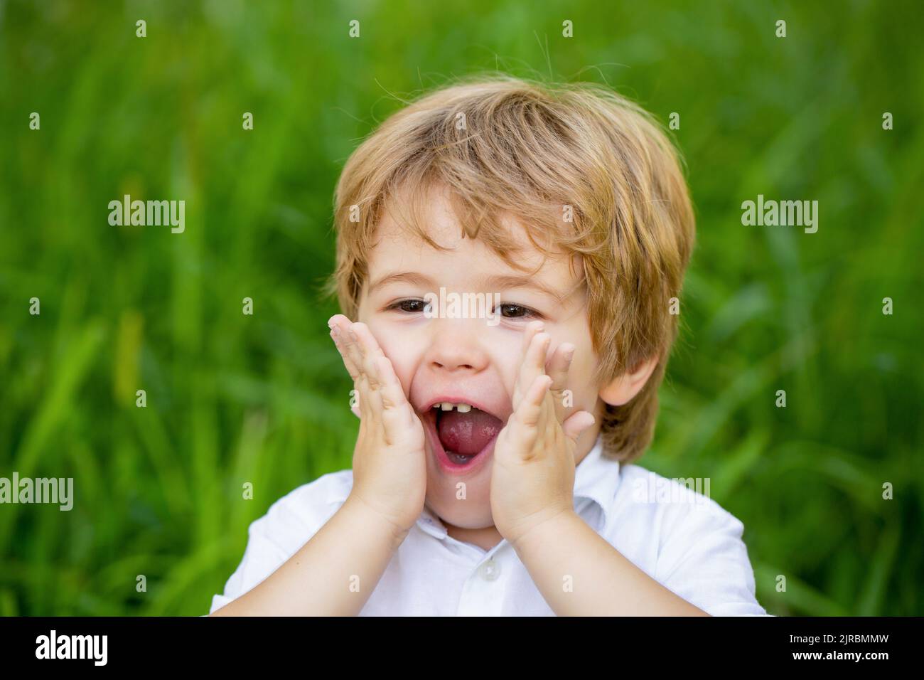 Child expressing surprise with his hands in his face. Smiling amazed or ...
