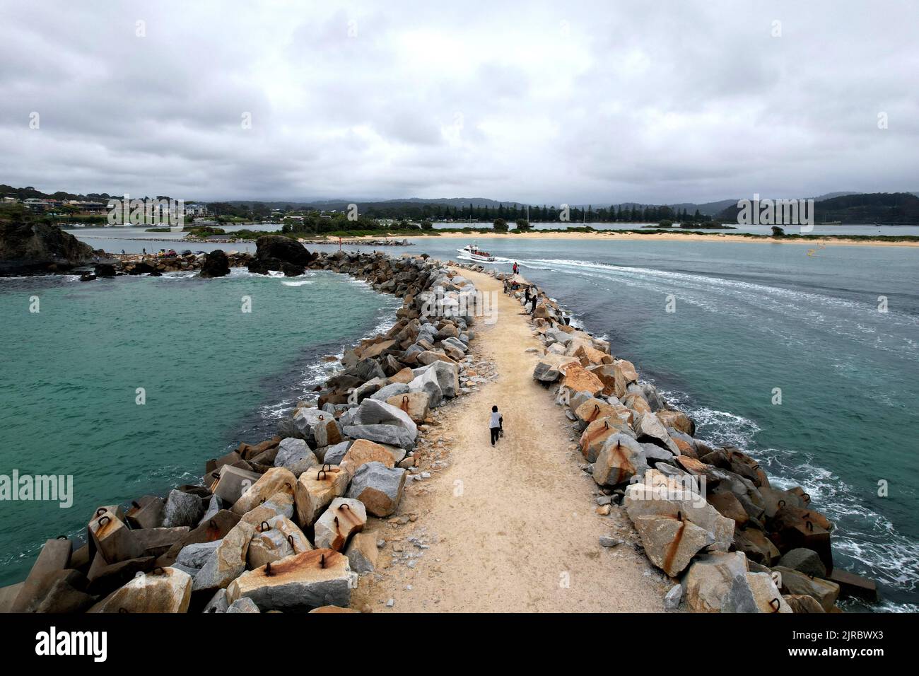 An aerial shot of a path with rocks and ocean on both sides and a ...