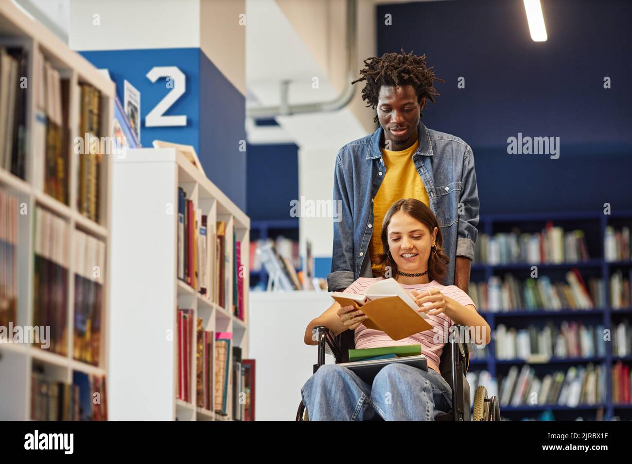 Portrait of young black man assisting female student with disability in ...