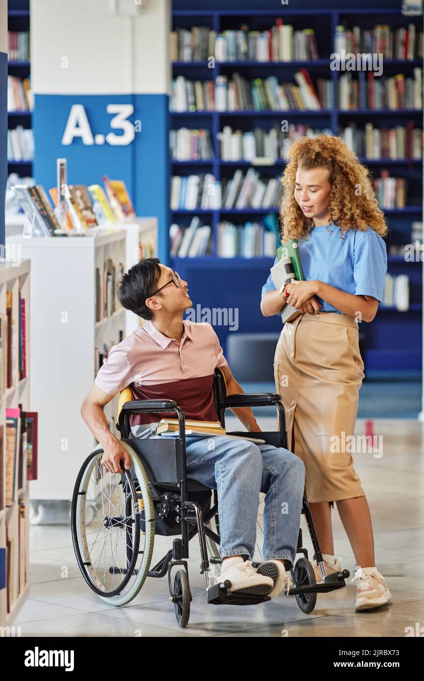 Vertical full length portrait of Asian student with disability talking ...