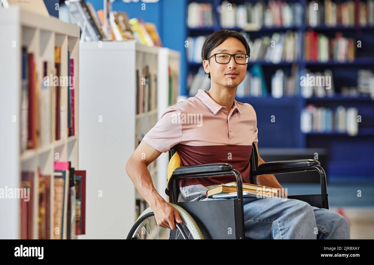 Vibrant portrait of Asian young man in wheelchair looking at camera in ...