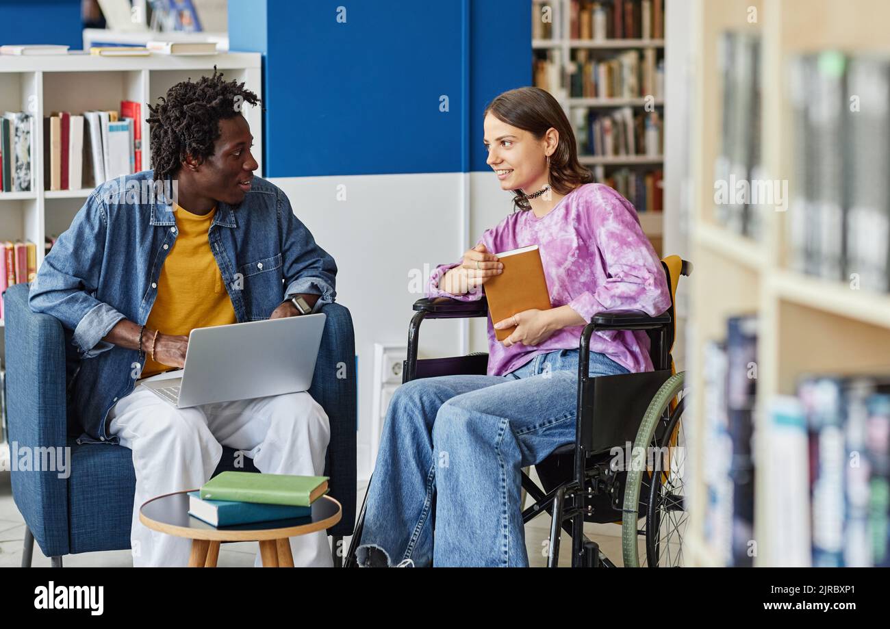 Portrait of smiling young woman with disability talking to friend while ...