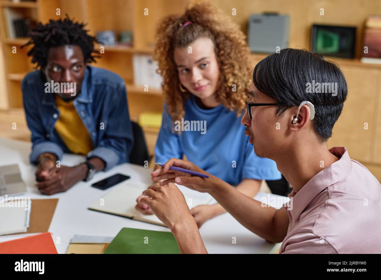 High angle portrait of young Asian man speaking to group of students in ...