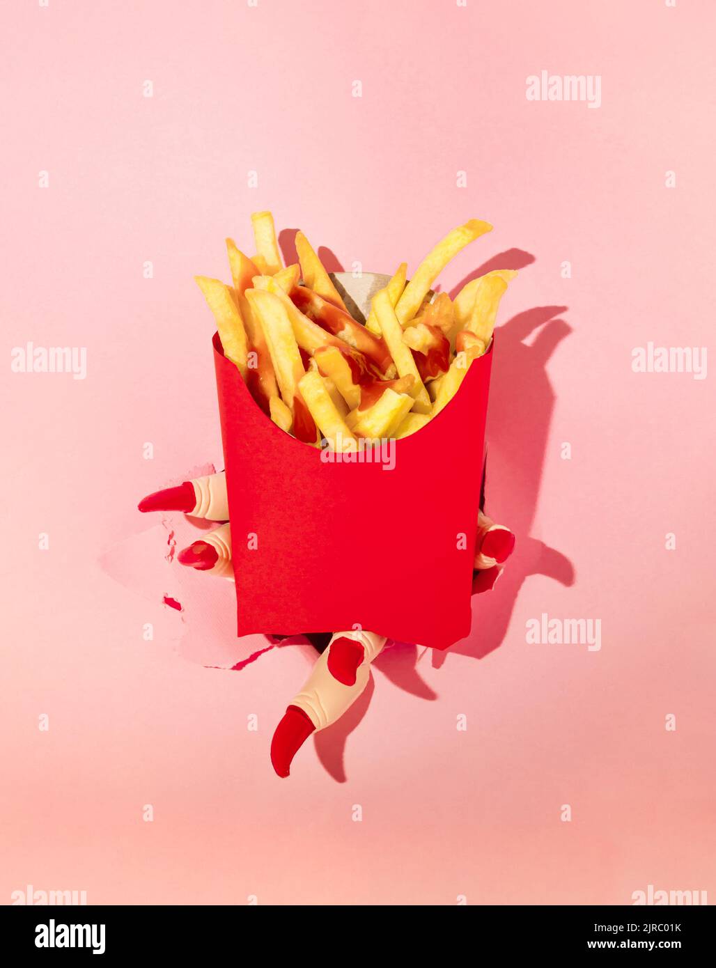 Creative layout made of hand with red nails holding french fries in red ...
