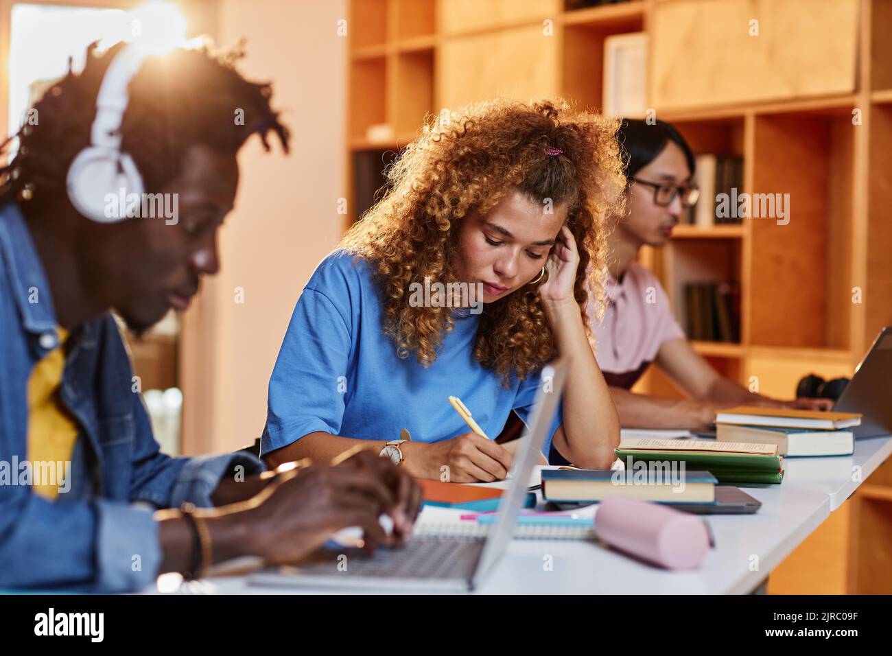 Diverse group of students in row studying in college library, focus on ...