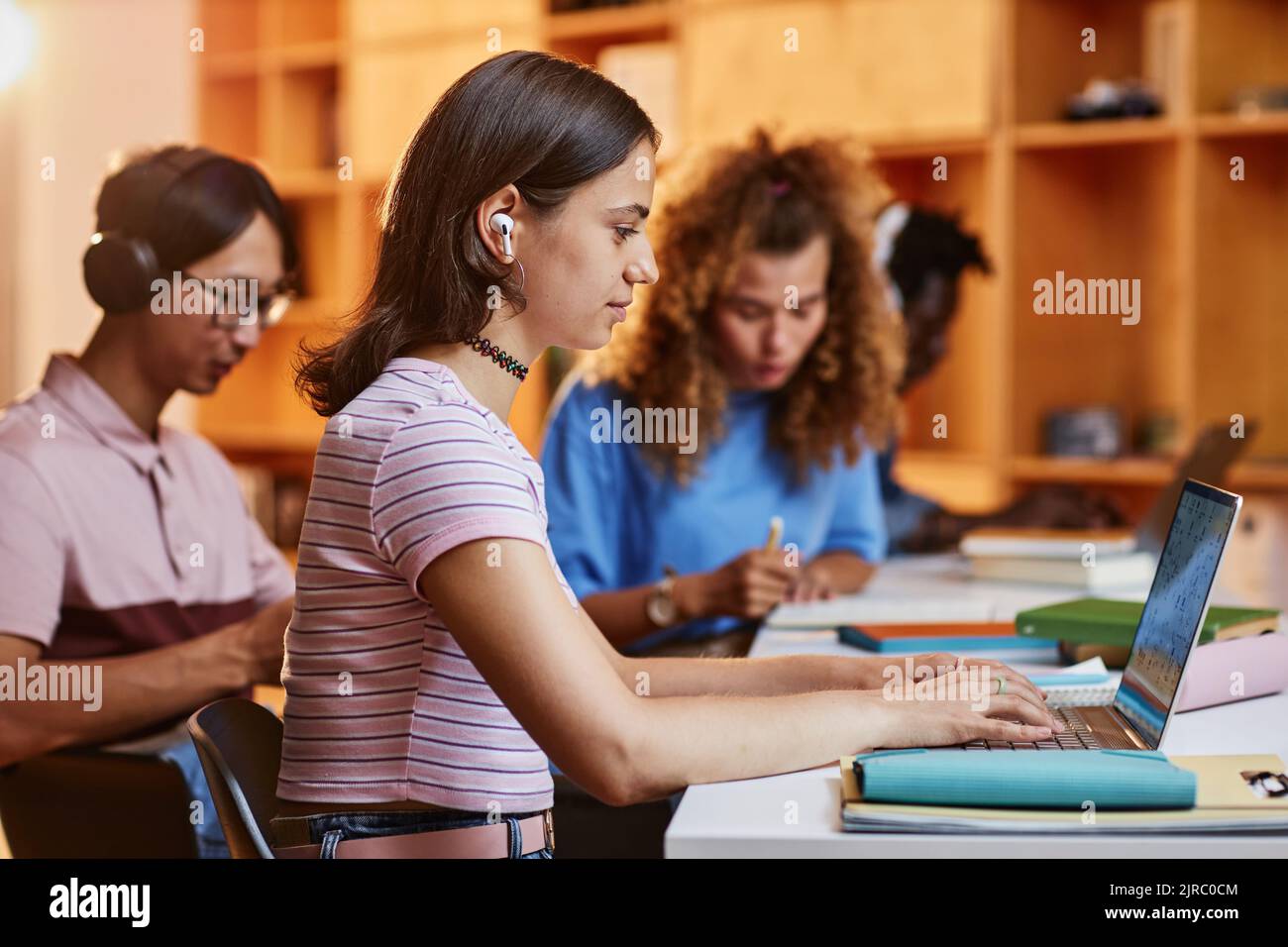 Diverse group of students in row using laptops and studying in college ...