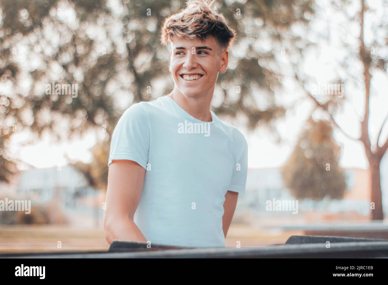 A young Spanish guy with blonde hair with a big smile in a park in ...