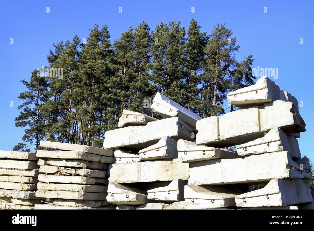 A pile of concrete building elements and a high trees in the background ...