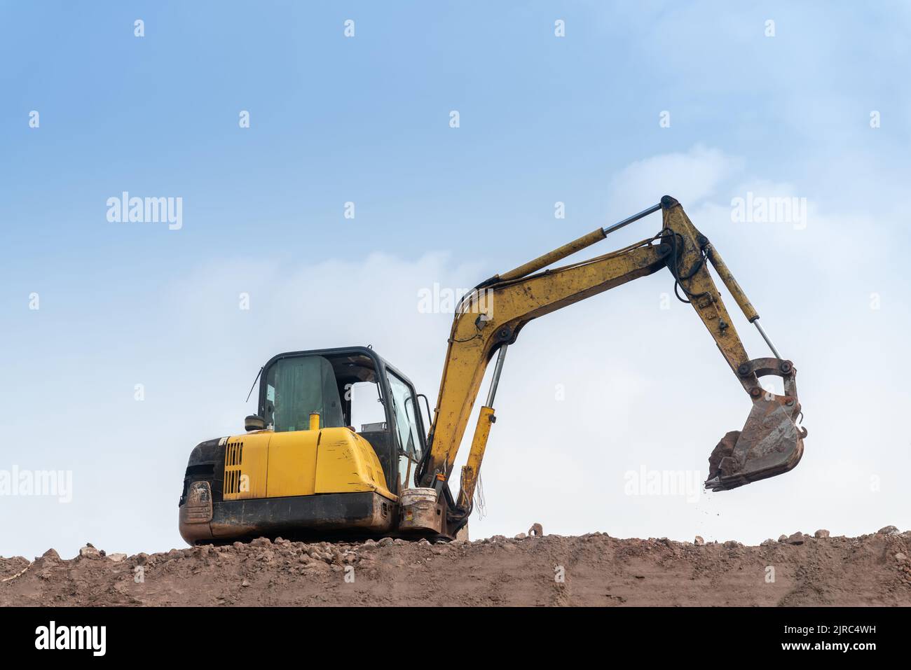 An excavator digging and loading dirt at the construction site with ...