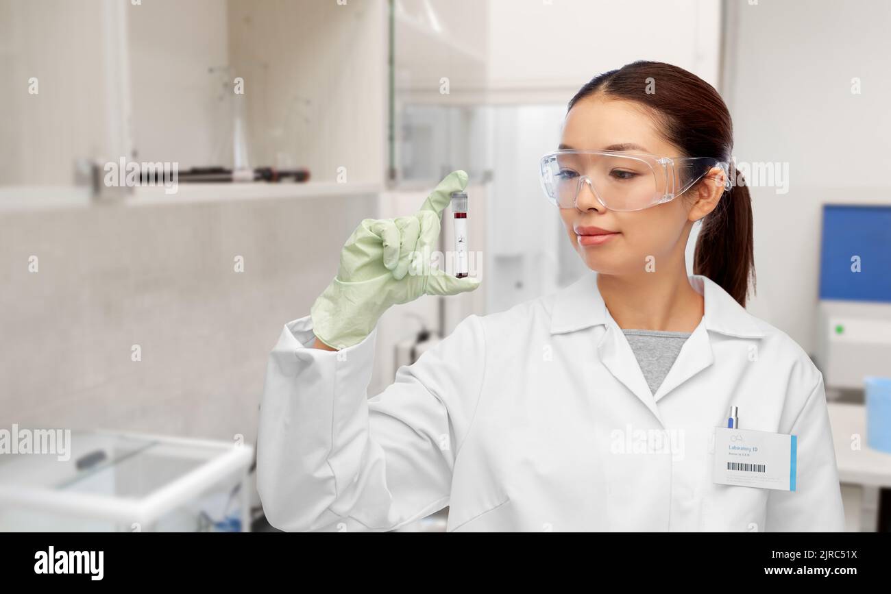 asian female doctor holding beaker with blood test Stock Photo - Alamy