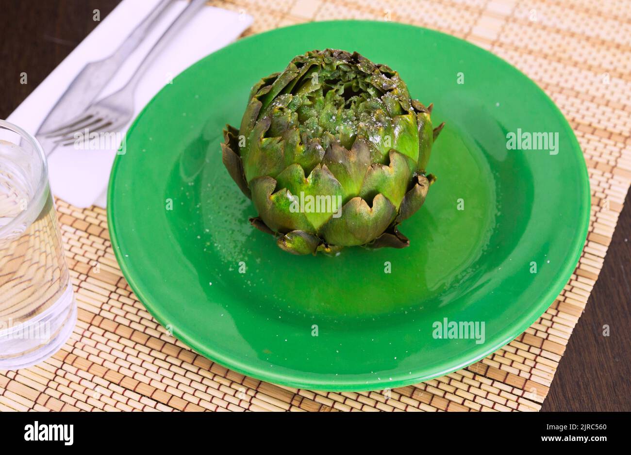 cooked whole artichoke on a green plate Stock Photo - Alamy