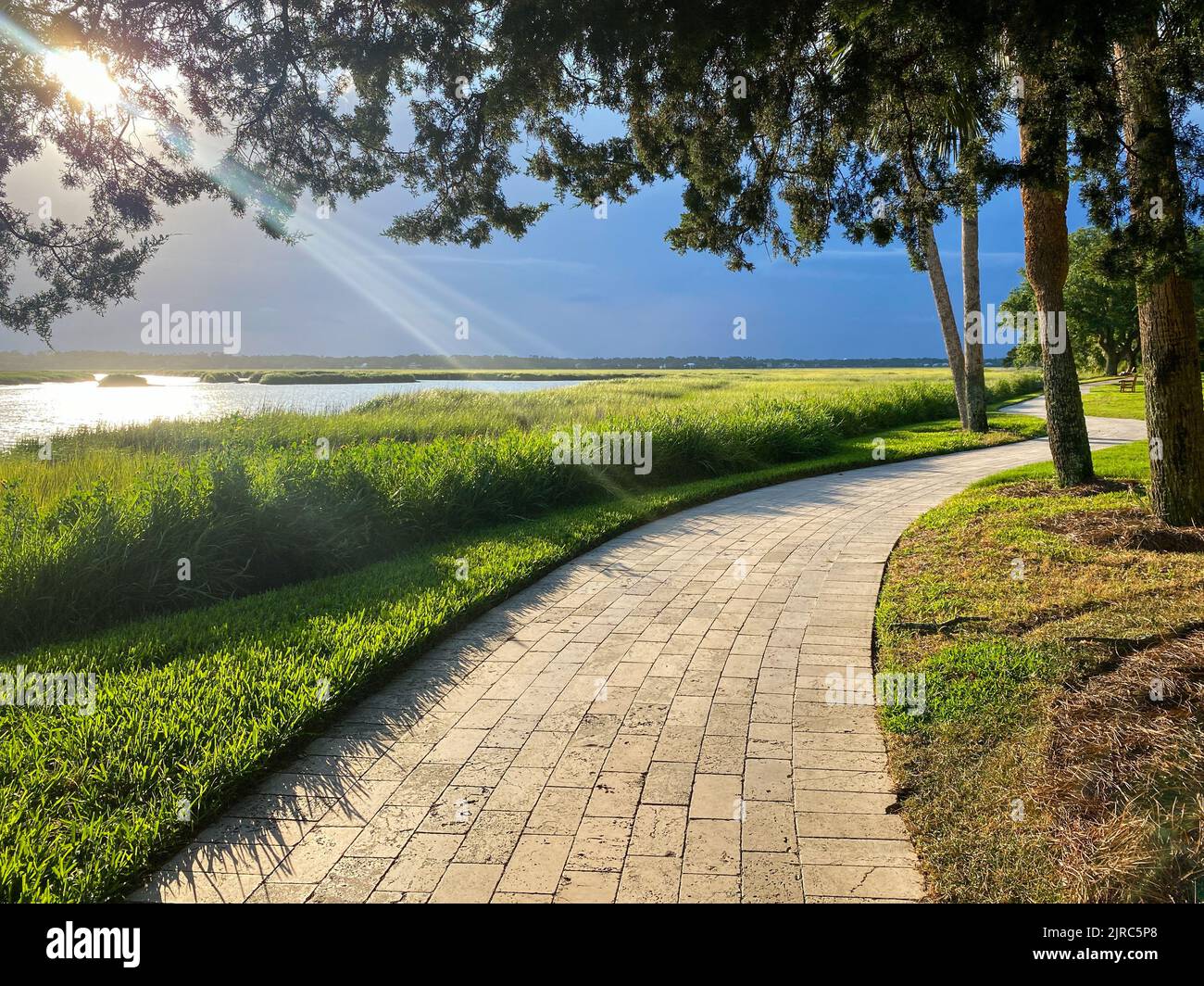 Peaceful brick path along a saltwater marsh with stormy skies and ...