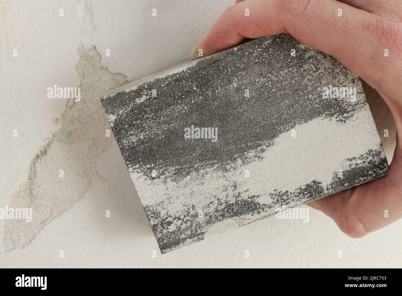 The person removes the old plaster with sandpaper. Home renovation ...