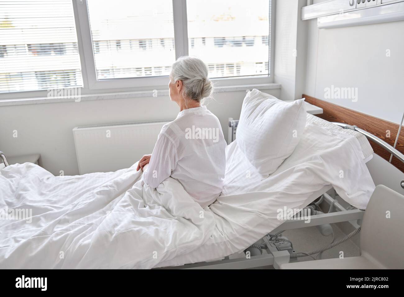 lonely senior woman sitting in bed at hospital Stock Photo - Alamy