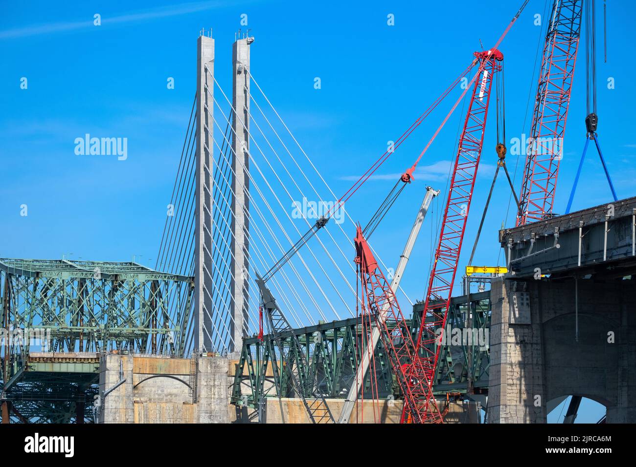 An old bridge is under demolition next to a new cable-stayed bridge ...