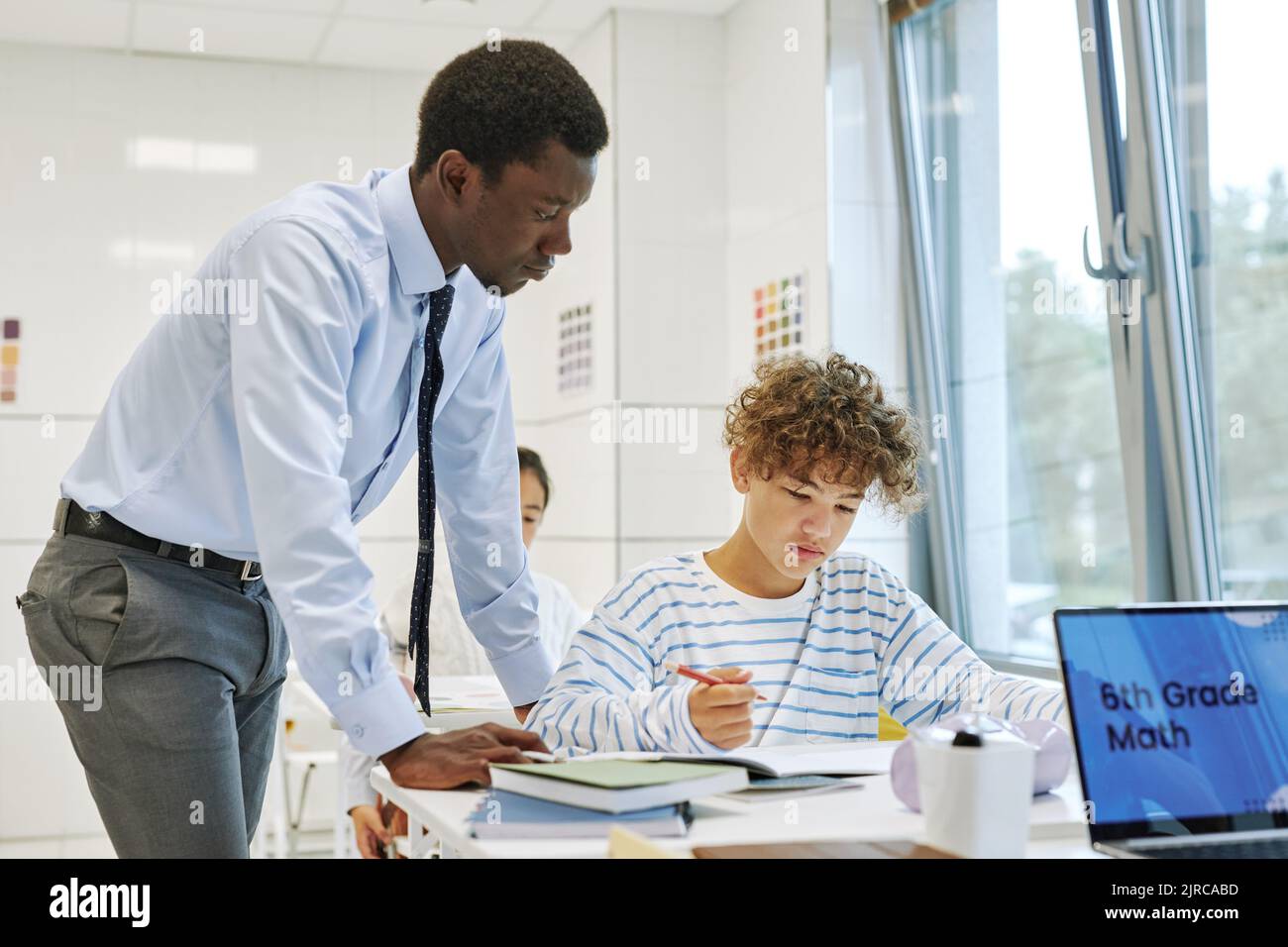 Side view portrait of young black teacher helping boy in school ...