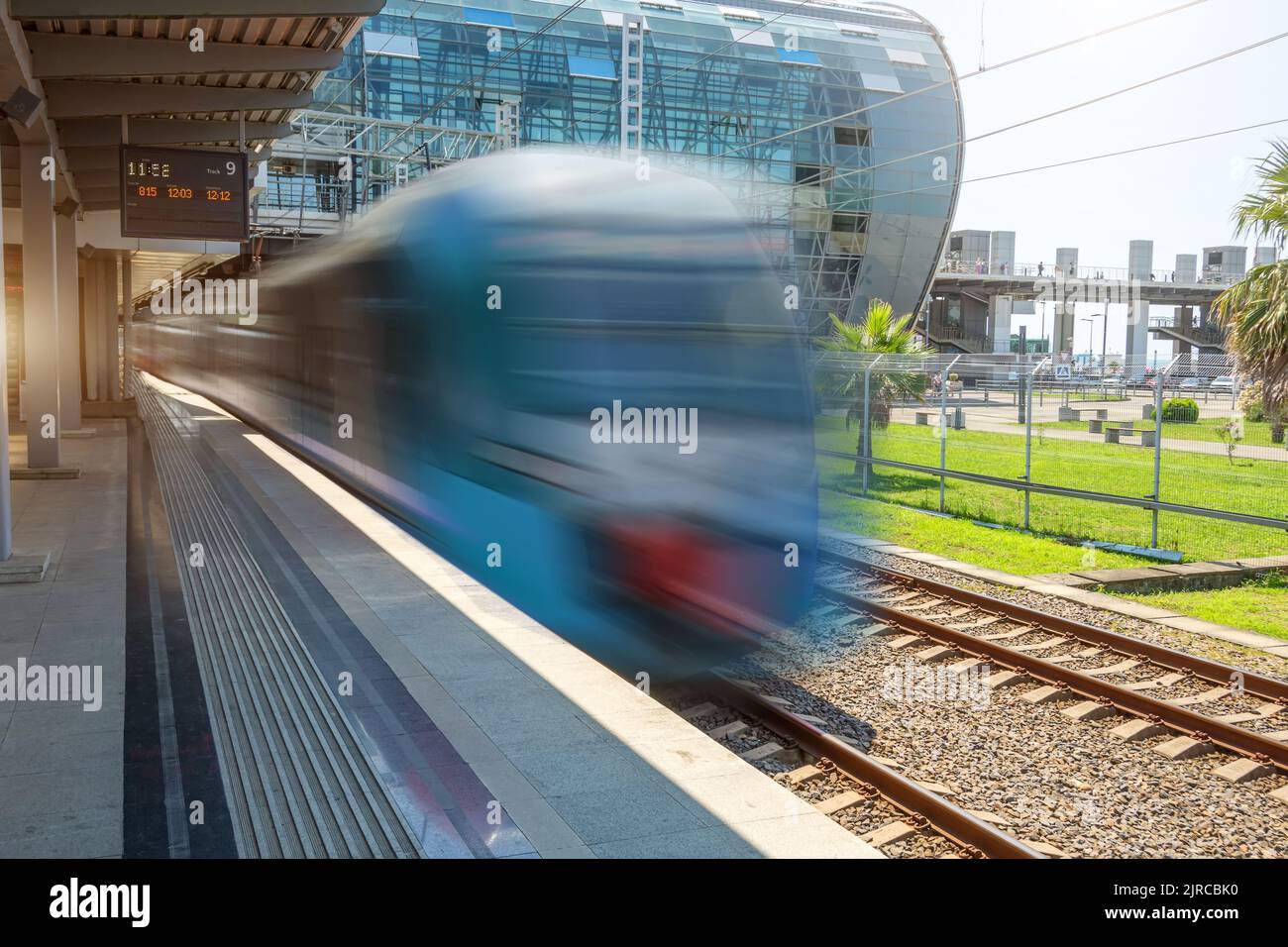 A train passing by next to the passenger platform on the railway tracks ...