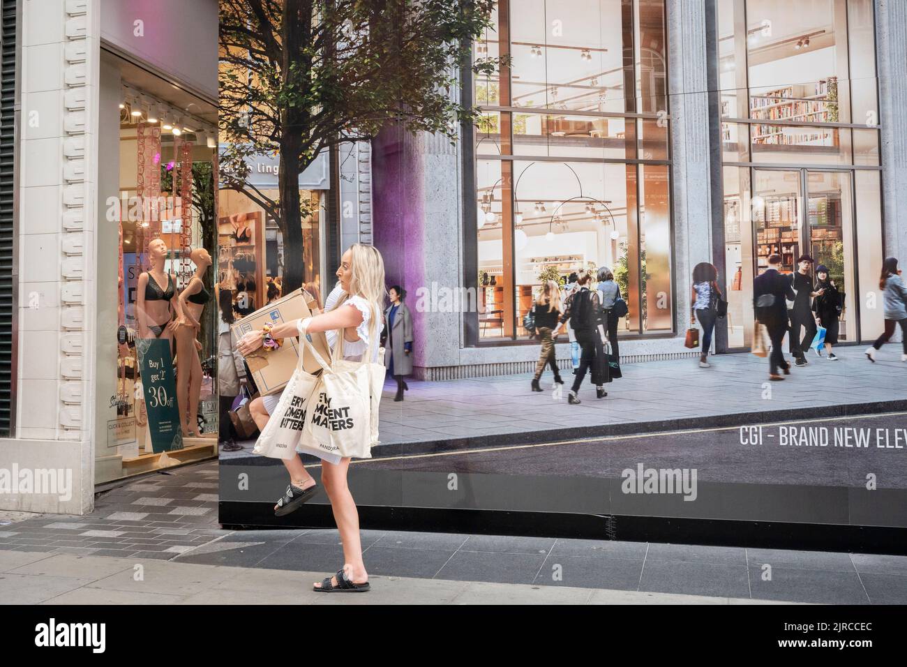 A woman struggles with a load of merchandise beneath a hoarding for a ...