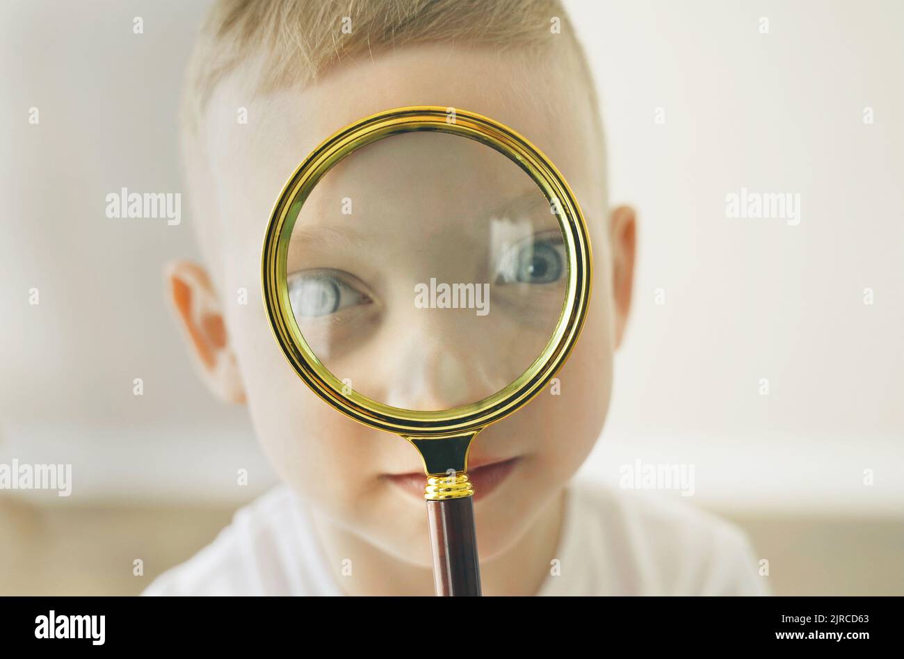 Faces of a boy holding a magnifying glass in his hand and looking ...
