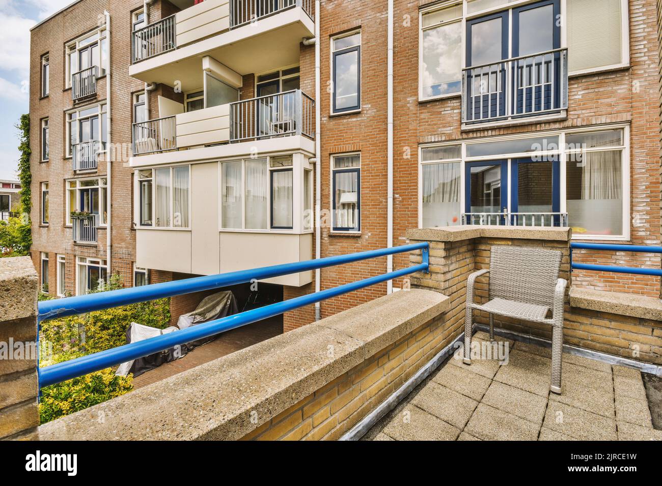 Narrow brick balcony with metal railings, wooden chair and door Stock ...