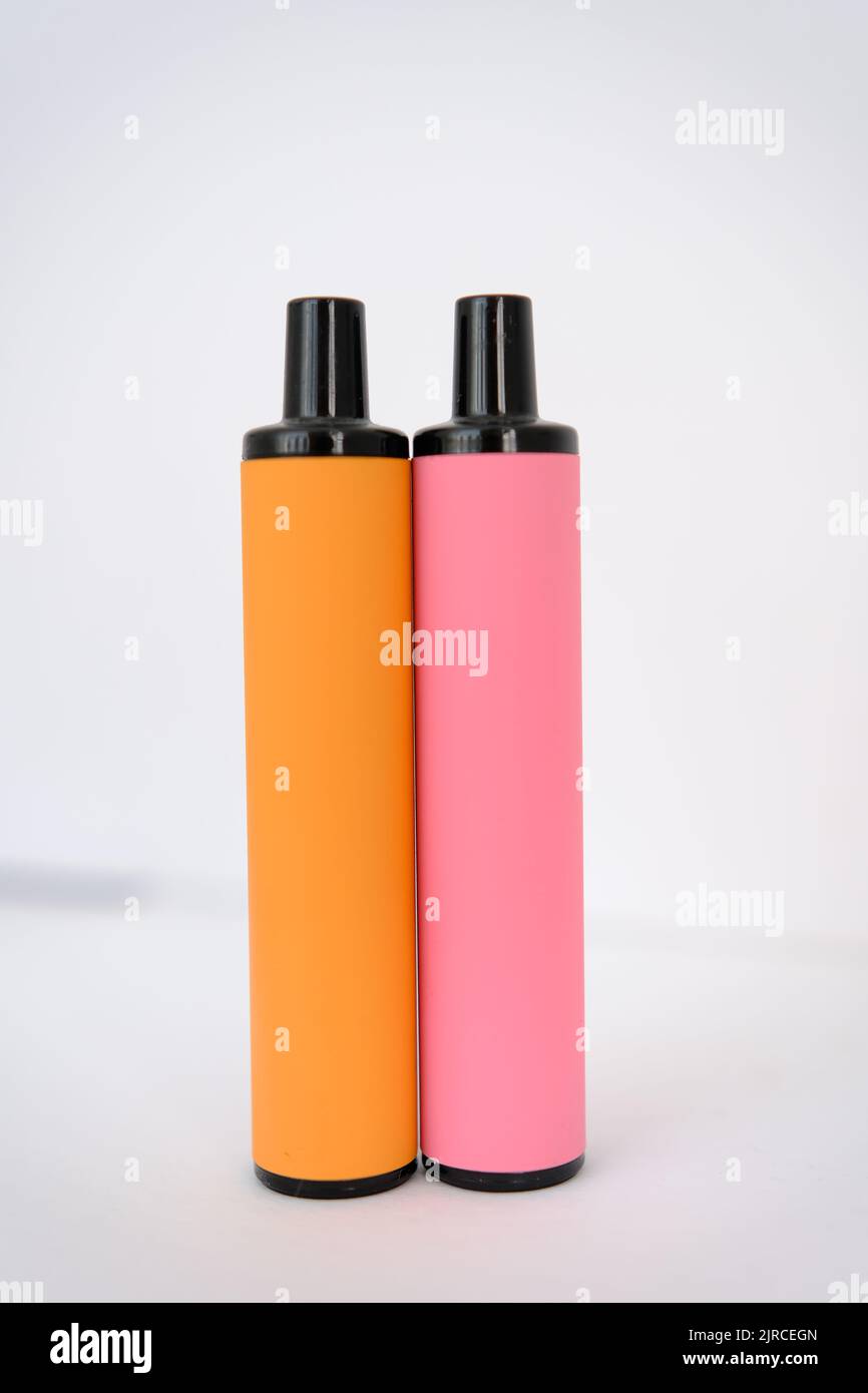 pink and orange disposable electronic cigarettes on white background ...