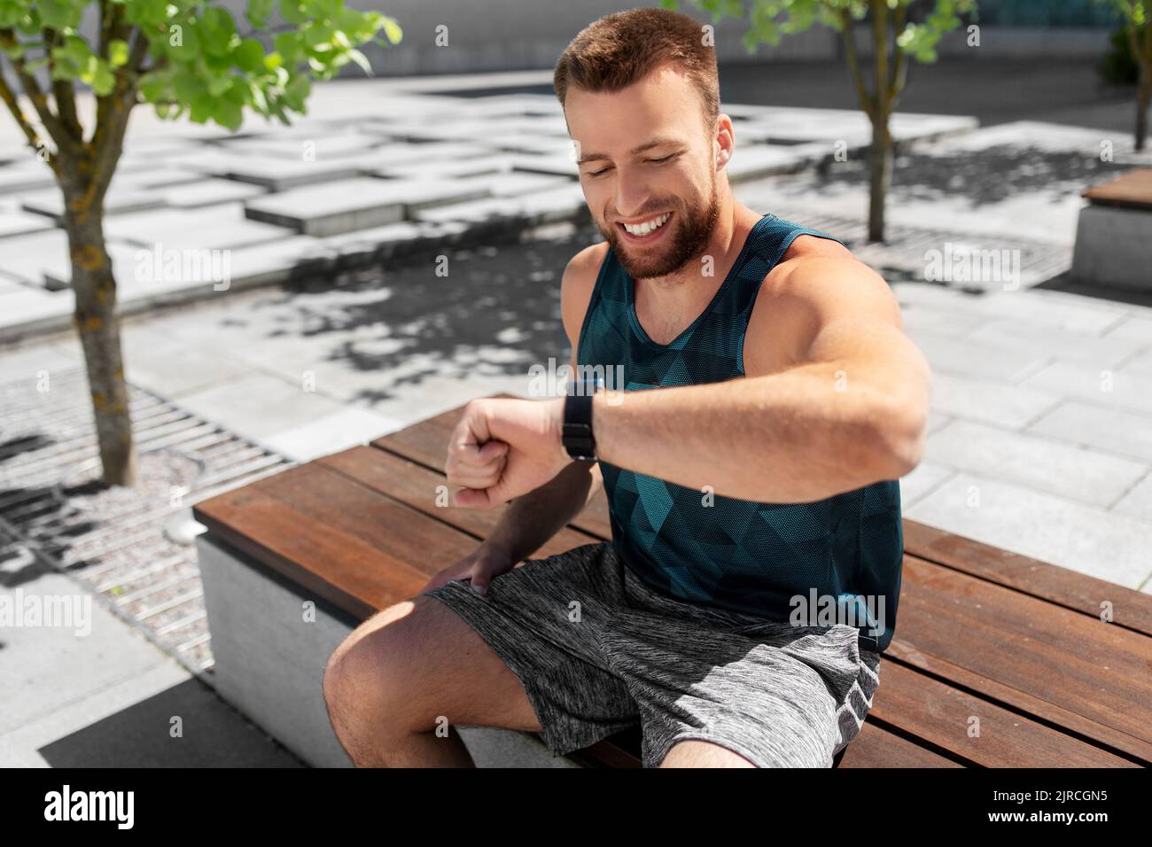 happy man with smart watch sitting on bench Stock Photo - Alamy