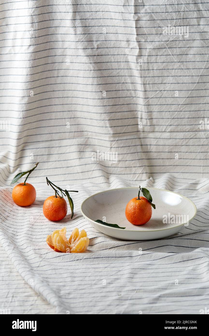 still life with mandarins on plate over drapery Stock Photo - Alamy