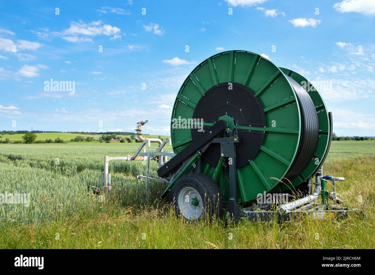 Agricultural irrigation system with a big hose reel in front of a wheat ...
