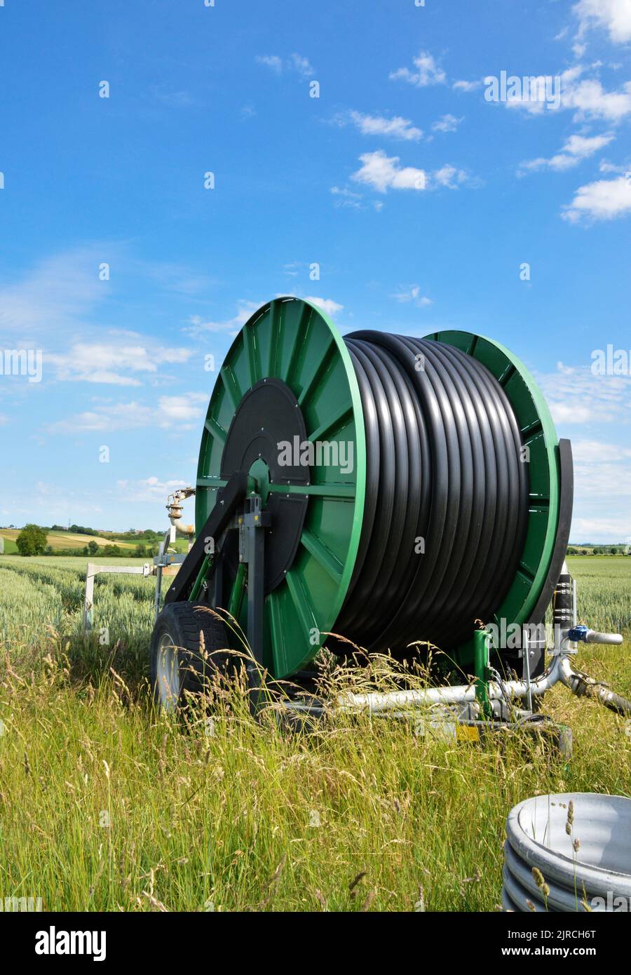 Agricultural irrigation system with a big hose reel in front of a wheat ...