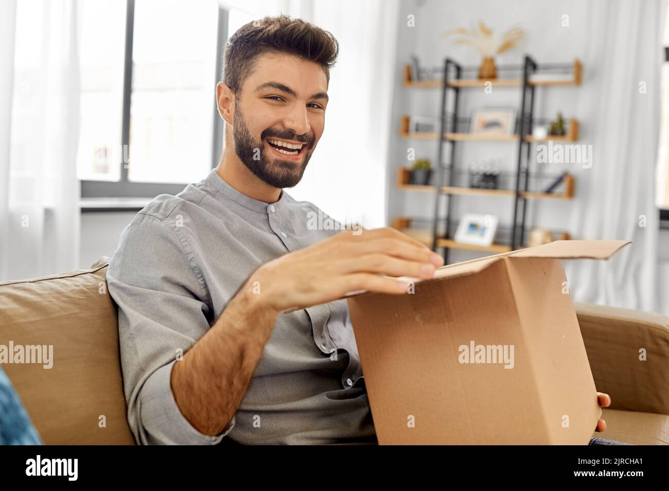 happy smiling man opening parcel box at home Stock Photo - Alamy