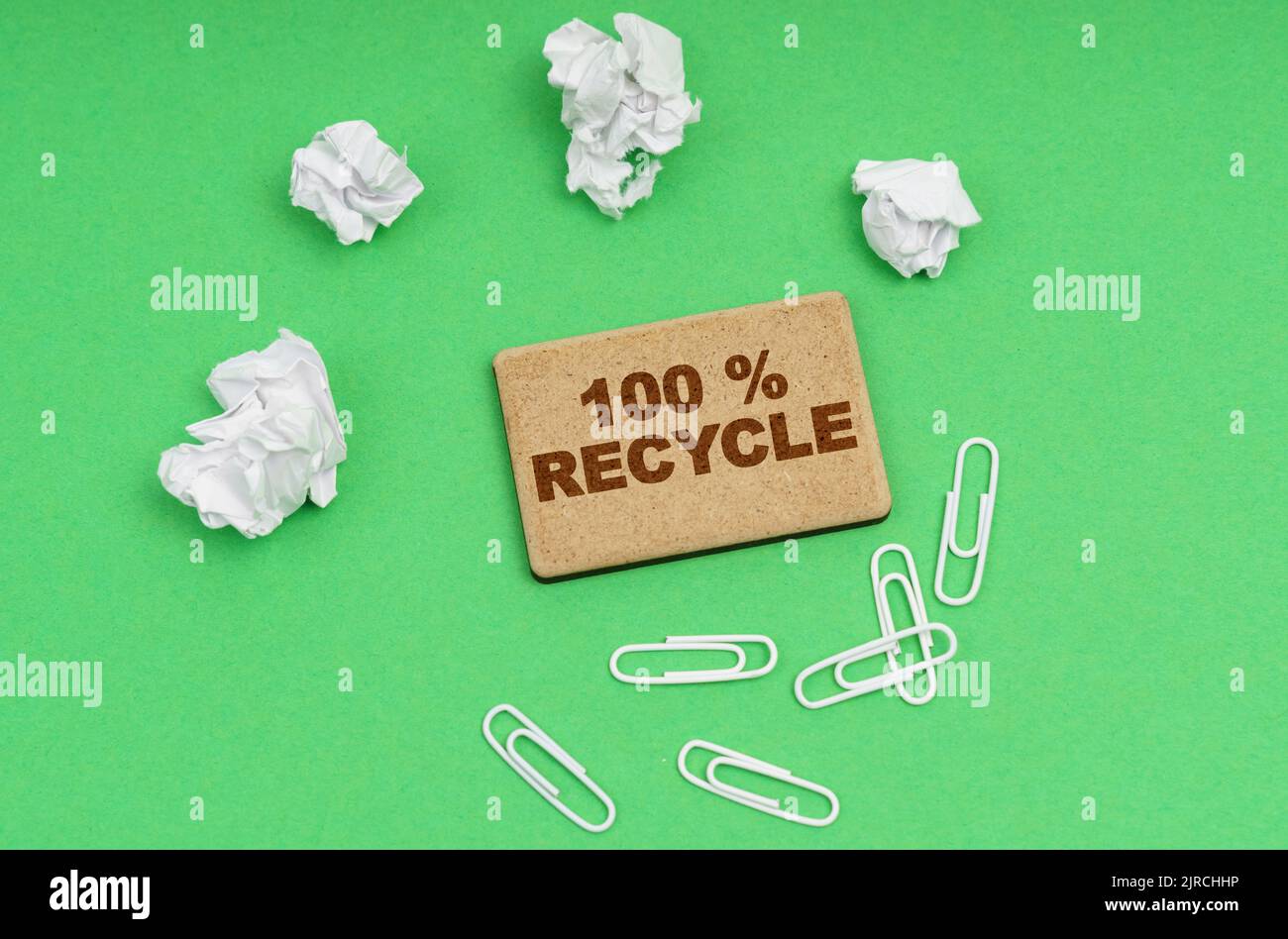 Ecology concept. On a green background, crumpled paper, paper clips and ...