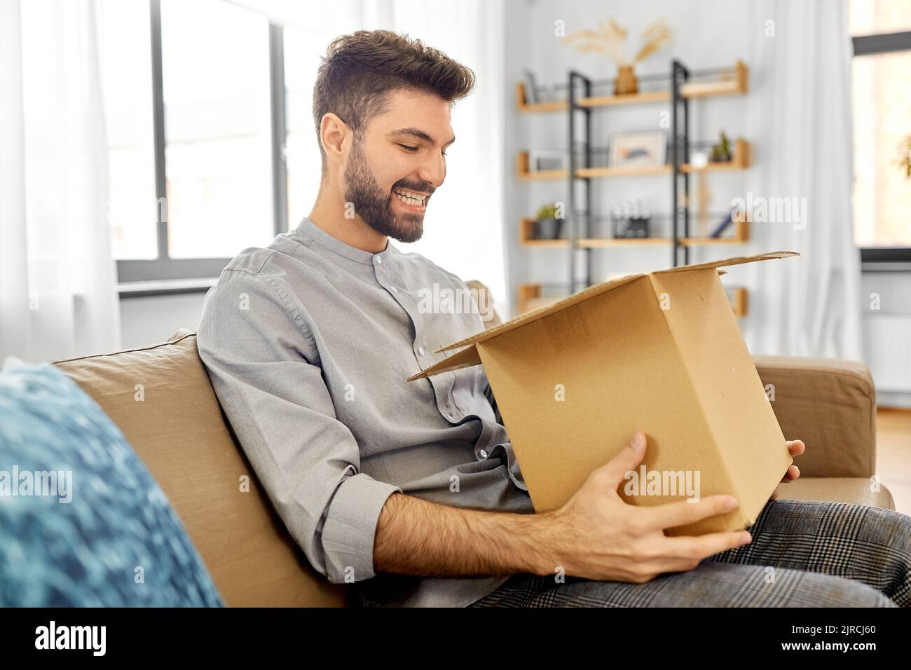 happy smiling man opening parcel box at home Stock Photo - Alamy
