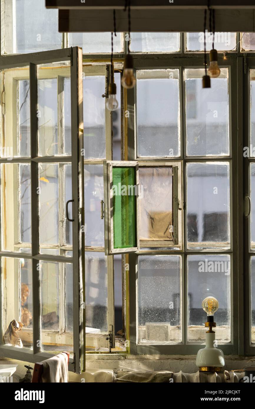 Old window frame painted in white color with stained glass and light ...