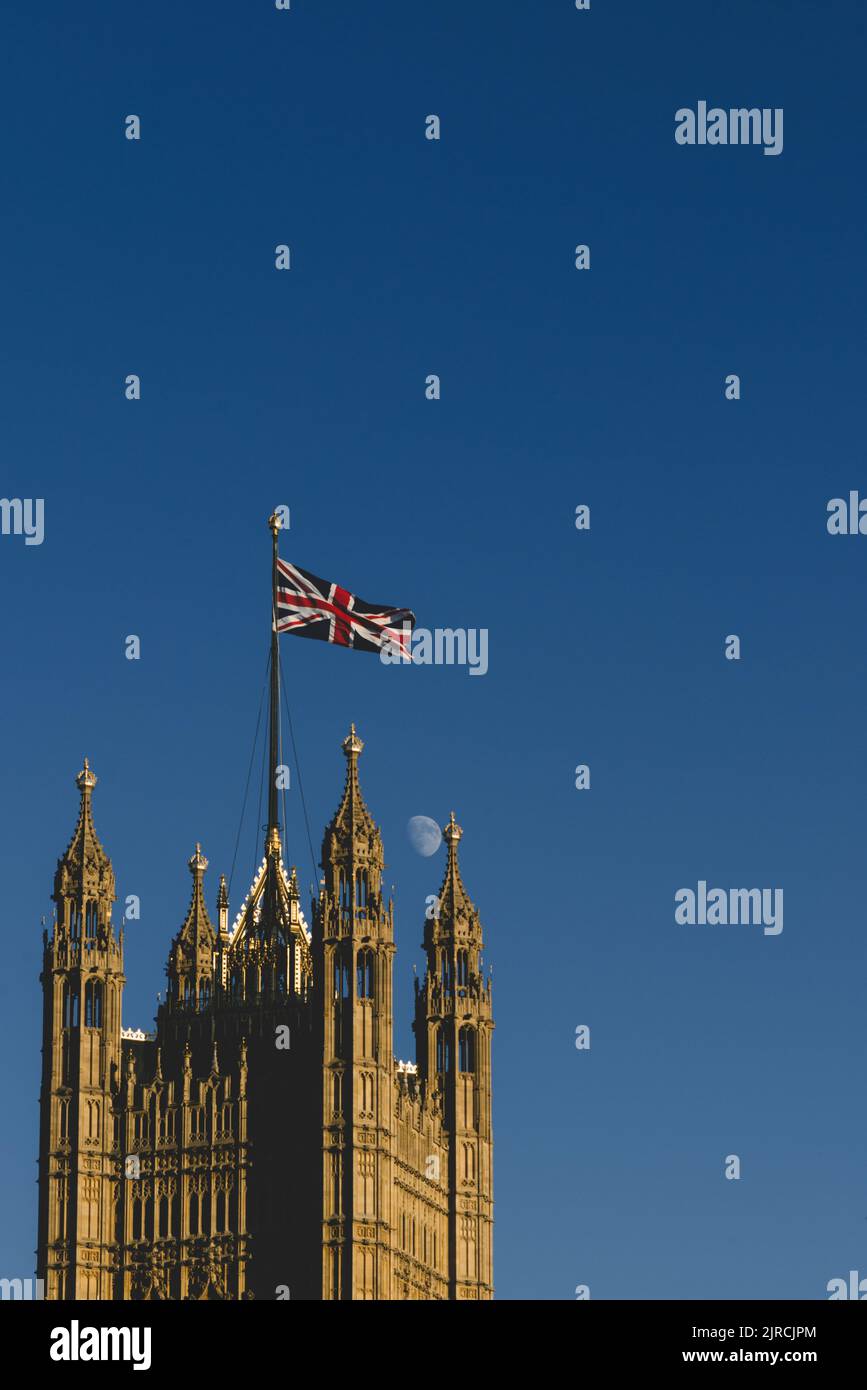 A vertical shot of the British flag on Victoria Tower on blue sky ...