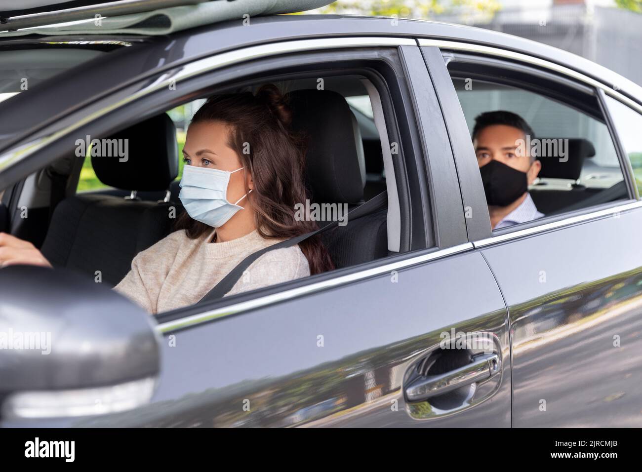female driver in mask driving car with passenger Stock Photo - Alamy