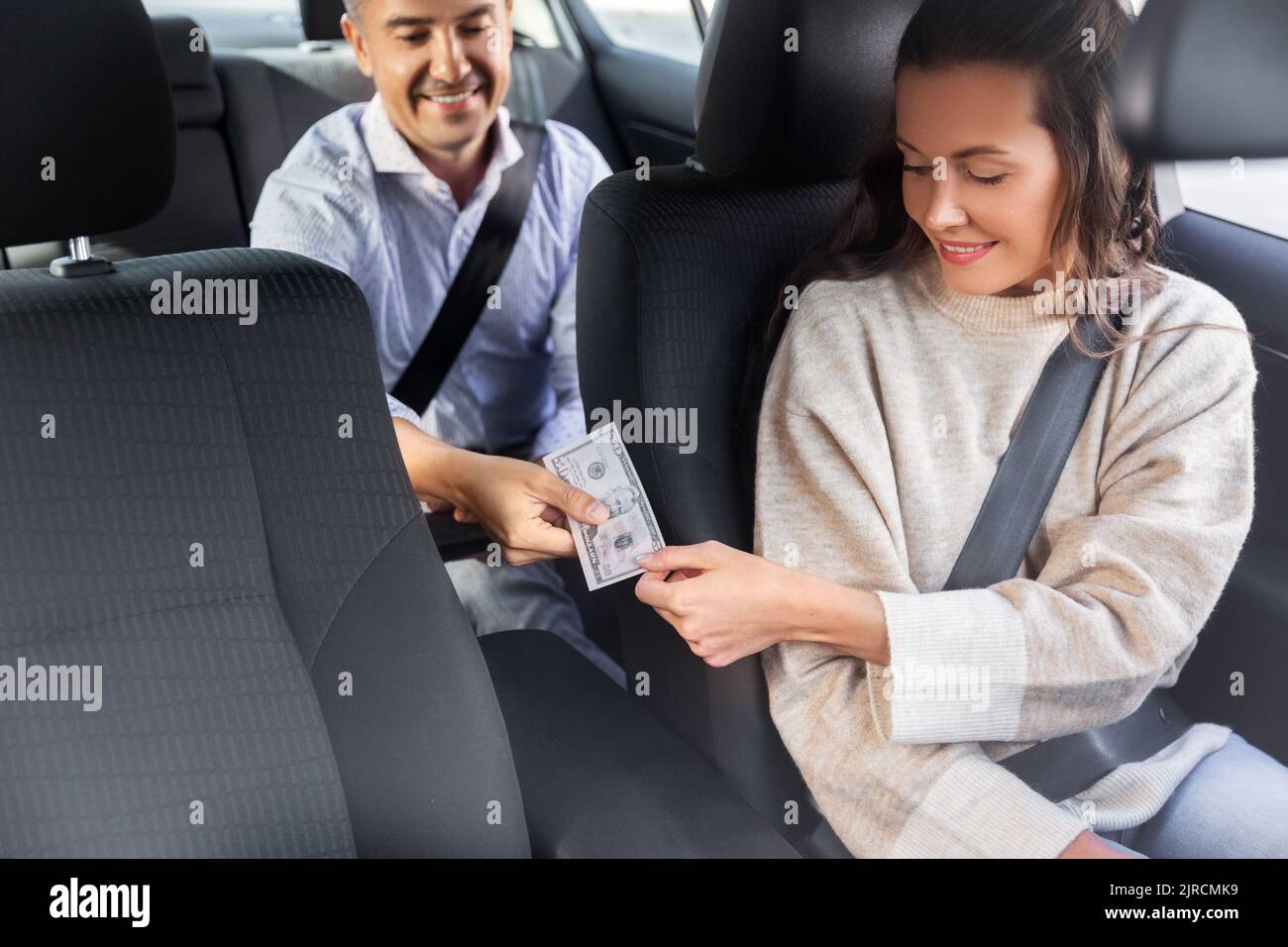 female car driver taking money from passenger Stock Photo - Alamy