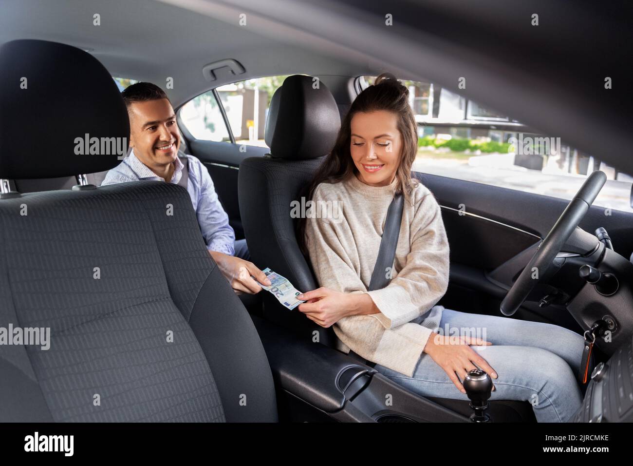 female car driver taking money from passenger Stock Photo - Alamy