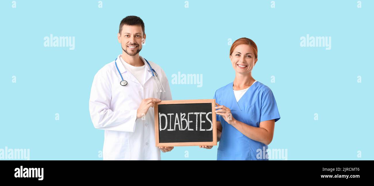 Doctors holding chalkboard with word DIABETES on light blue background ...