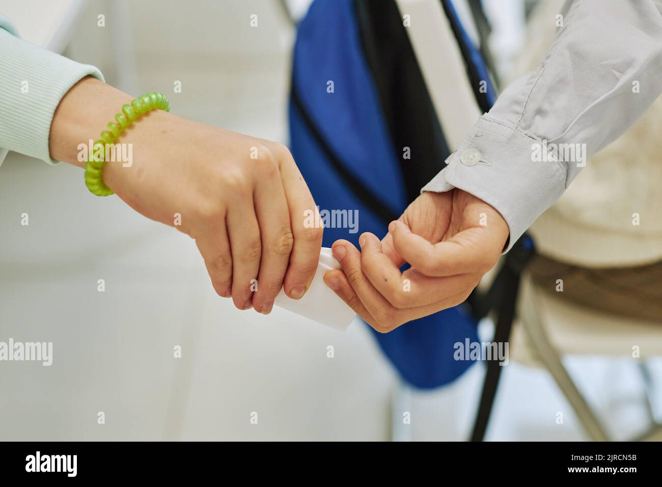 Close up of two unrecognizable children passing note in secret during ...