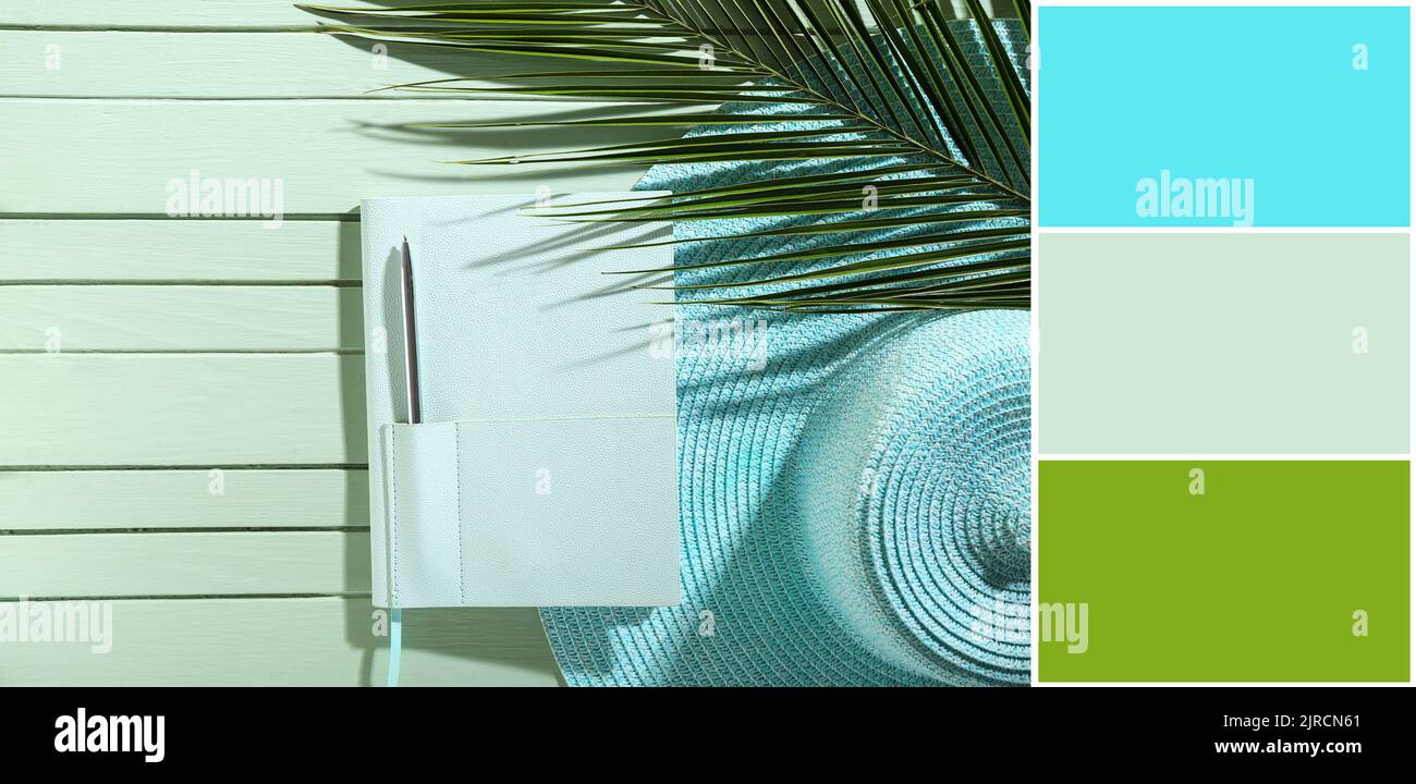 Stylish notebook with pen, hat and palm leaf on green wooden background ... Stylish notebook with pen, hat and palm leaf on green wooden background ...