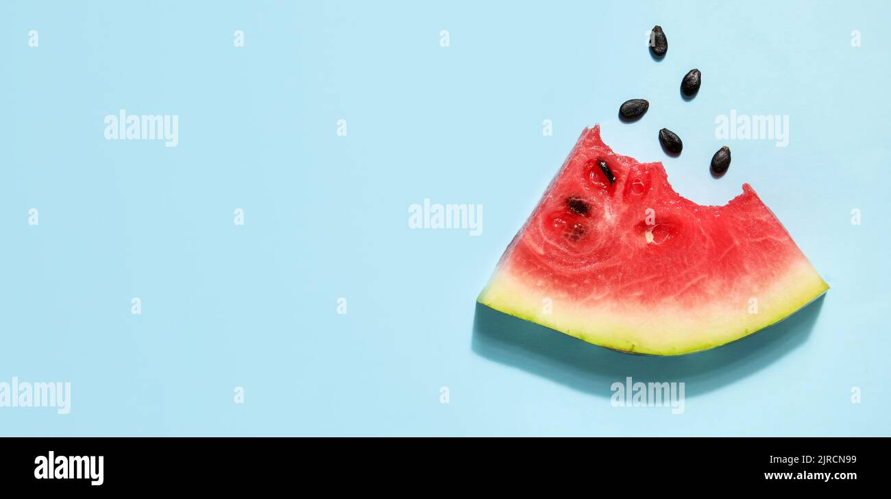 Bitten slice of watermelon with seeds on blue background with space for ...