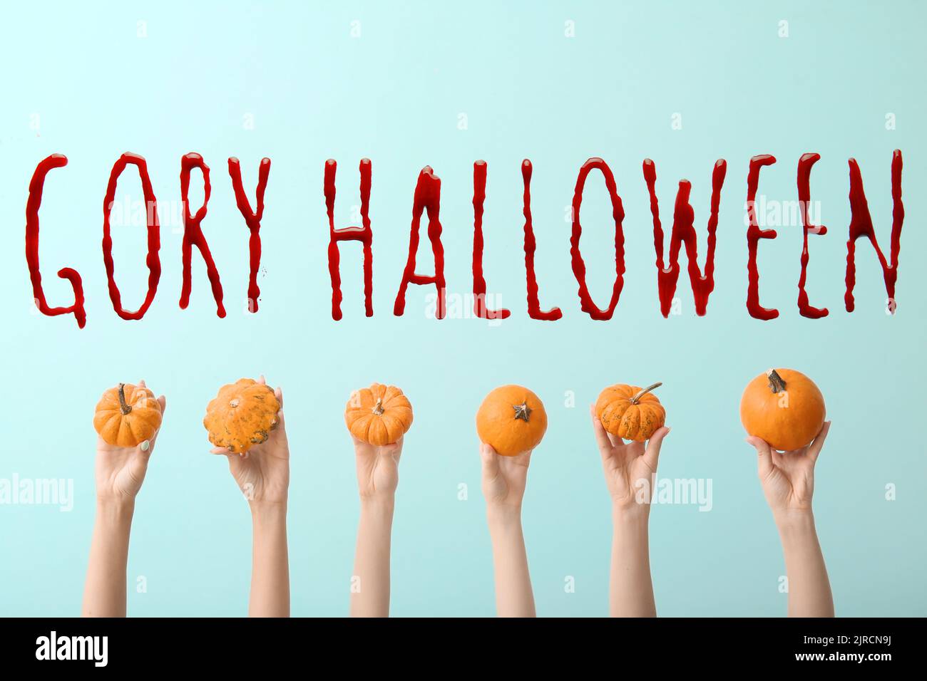 Female hands with pumpkins and text GORY HALLOWEEN on light blue ...