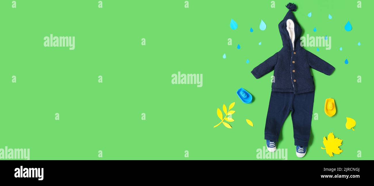 Stylish autumn baby clothes on green background with space for text ...