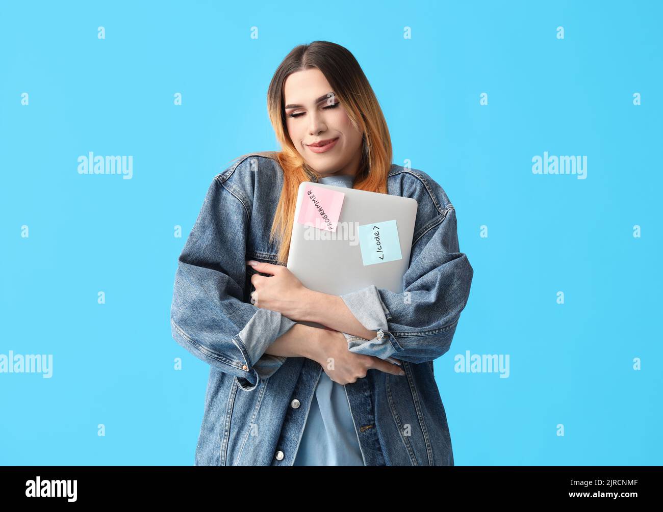 Transgender programmer with laptop on blue background Stock Photo - Alamy