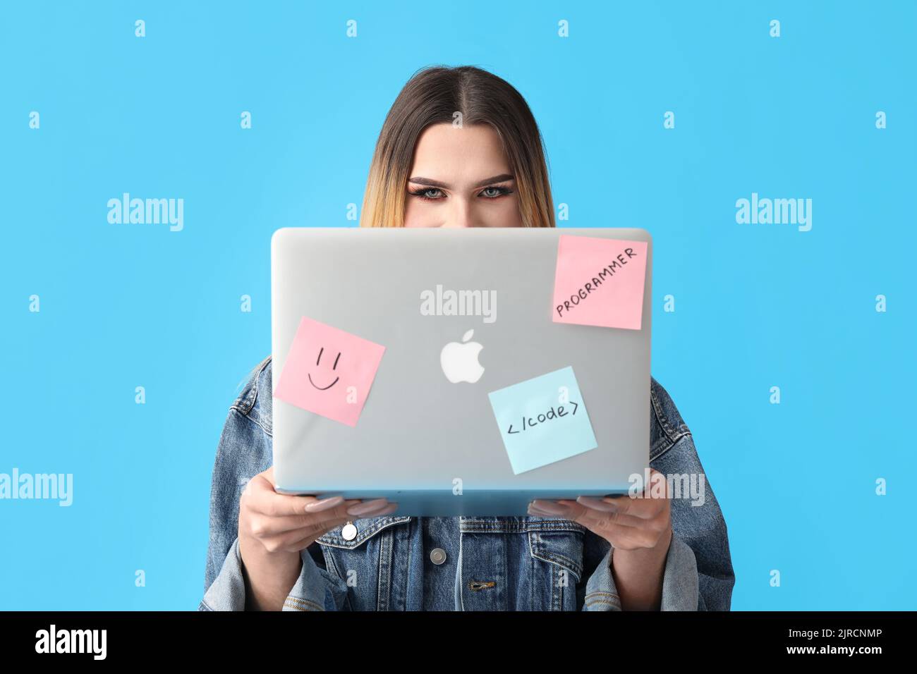 Transgender programmer with laptop on blue background Stock Photo - Alamy