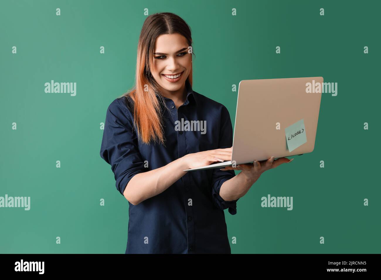 Transgender programmer with laptop on green background Stock Photo - Alamy