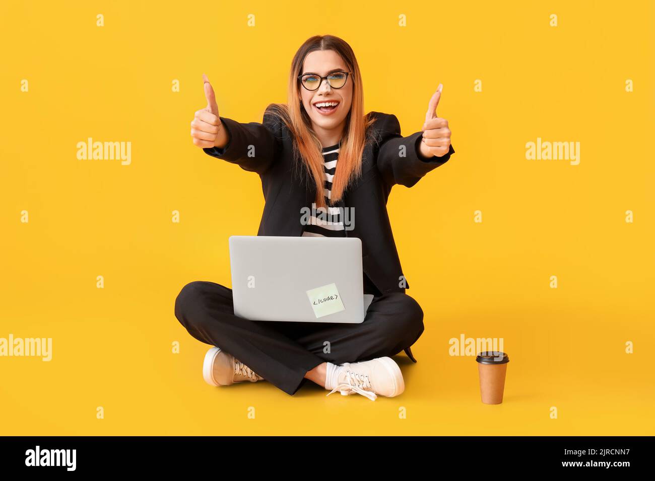 Transgender programmer with laptop showing thumb-up on yellow ...