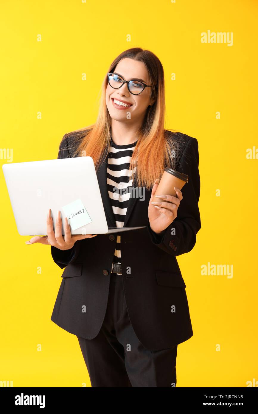 Transgender programmer with laptop and coffee on yellow background ...
