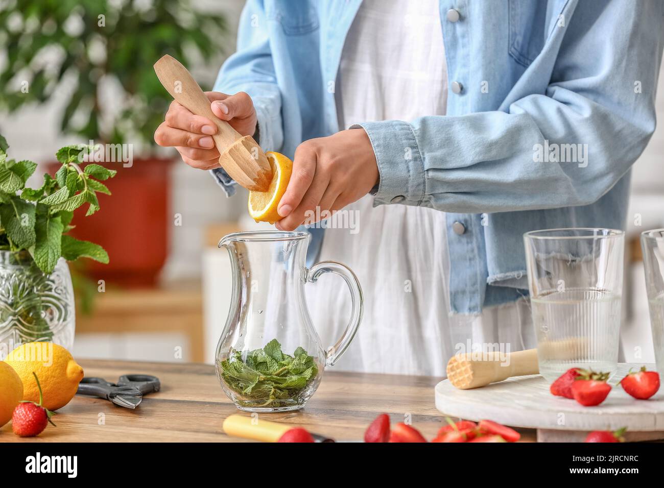 Woman squeezing lemon juice into jug in kitchen Stock Photo - Alamy